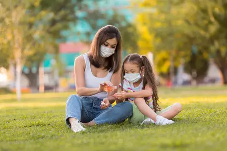 Azijos mama ir dukra naudoja dezinfekavimo priemonę lauke