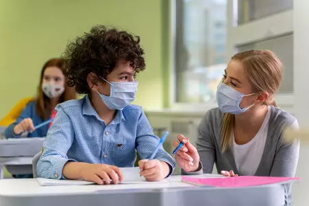 クラスの学生を助ける医療マスクを持つ女教師