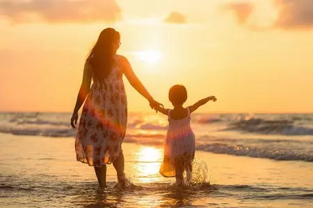 Motina ir dukra ant kranto saulėlydžio metu