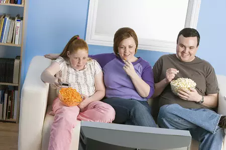 Familie spiser foran fjernsynet