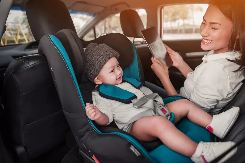 Où l'enfant place-t-il les jambes lorsqu'il voyage dos à la route ?