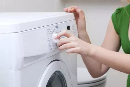 Người phụ nữ đang bật máy giặt