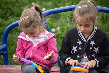 Enfants jouant avec le jouet populaire Pop It tenir dans leurs mains jeu de silicone anti-stress